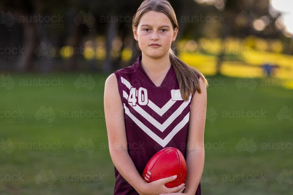 Image of tween girl wearing footy jersey looking at camera holding a ...