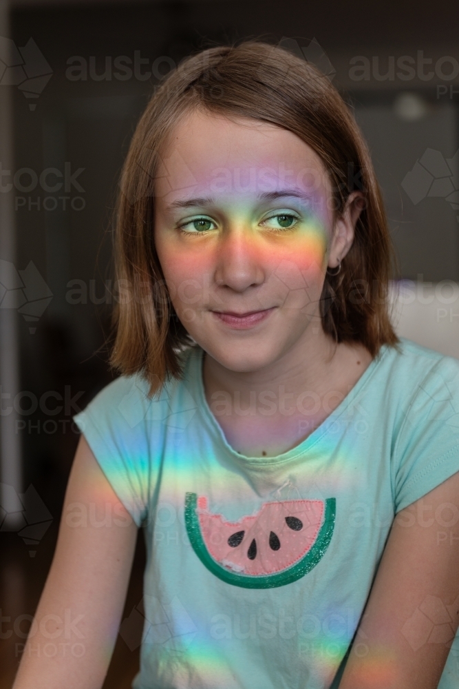 Image of Tween girl with rainbow shadow on her face - Austockphoto