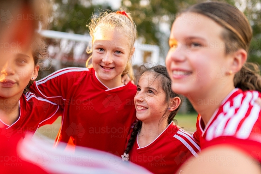 Image of Tween girls football team members in a close pre-game huddle ...