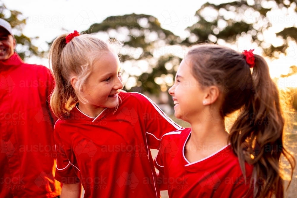 Image of Tween girls smiling at each other at a sports oval - Austockphoto