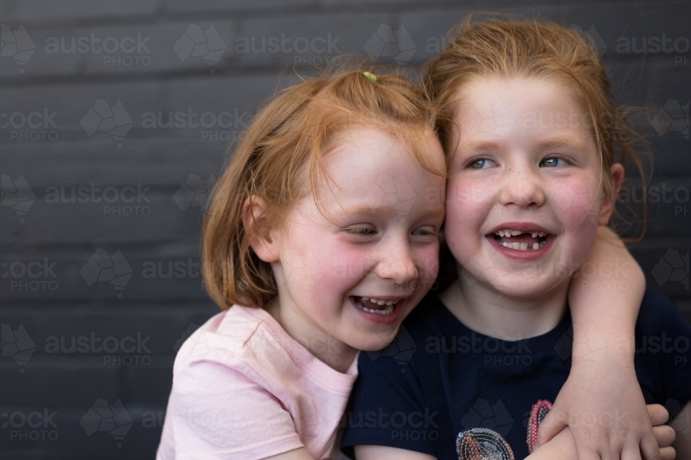 Image of Twin sisters hugging and smiling - Austockphoto