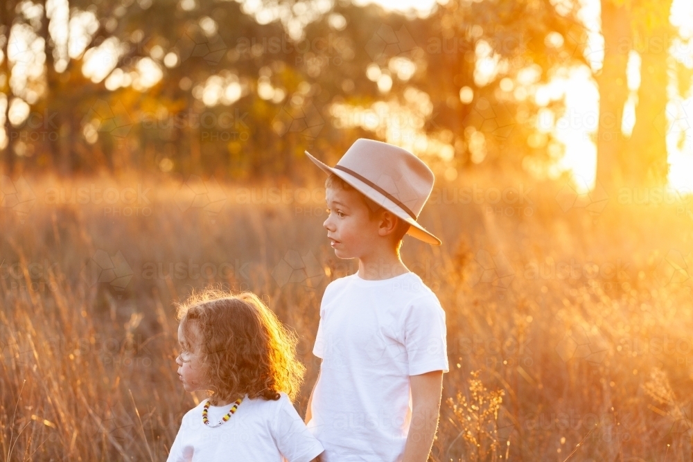 Image of Two aboriginal kids together in grassy paddock in golden ...