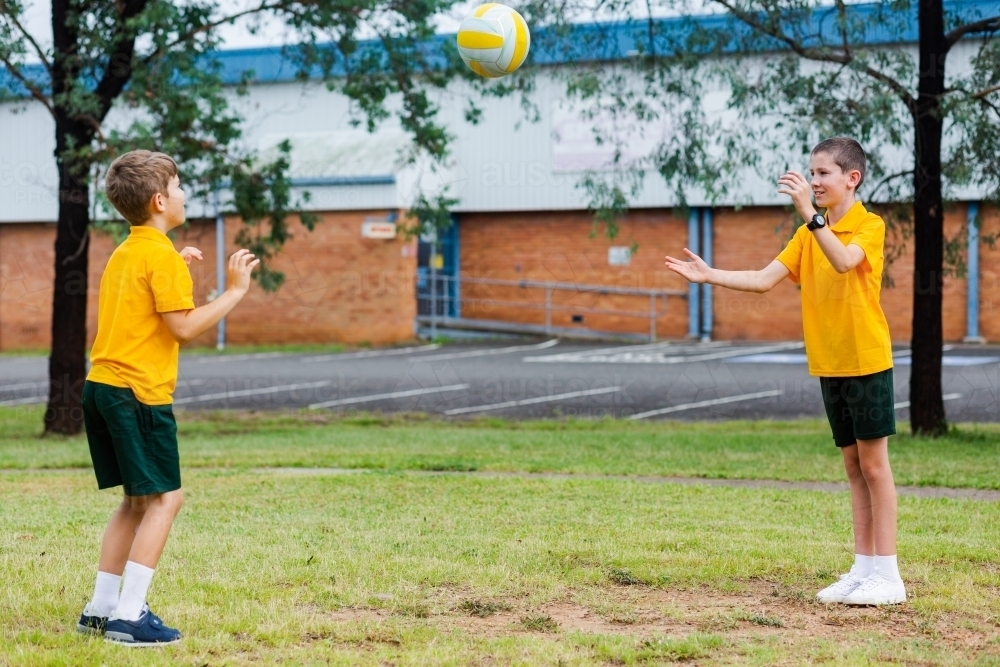 Image of Two Aussie school boys throwing a ball together outside ...