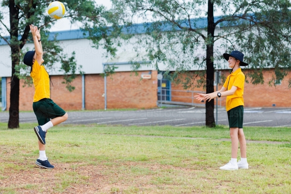 Image of Two Aussie school boys throwing a ball together outside ...