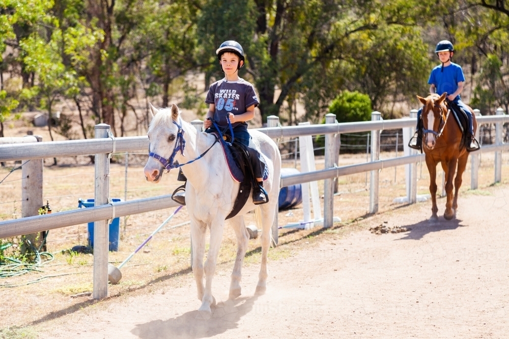 Image of Two boys having a horse riding lesson together - Austockphoto