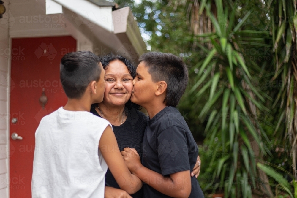 Image of two boys kissing their mum on both cheeks - Austockphoto