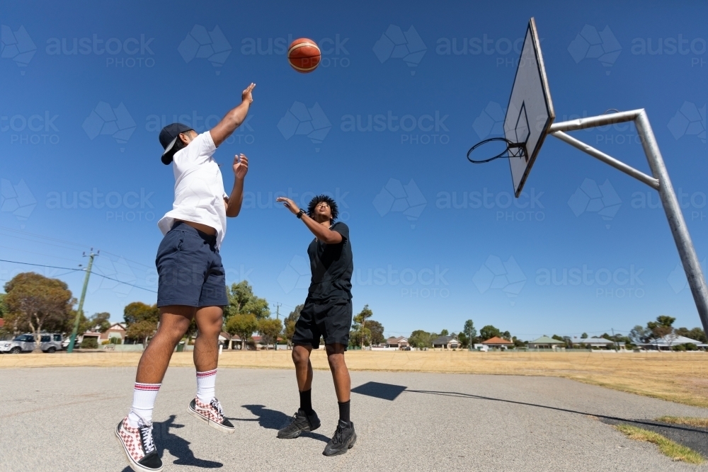 Image of two boys shooting basketball one on one in country town ...