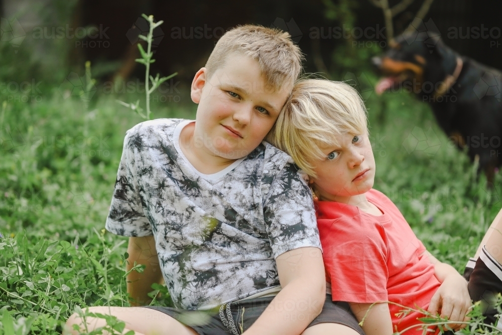 Image of Two brothers sitting together in natural setting sharing quiet ...
