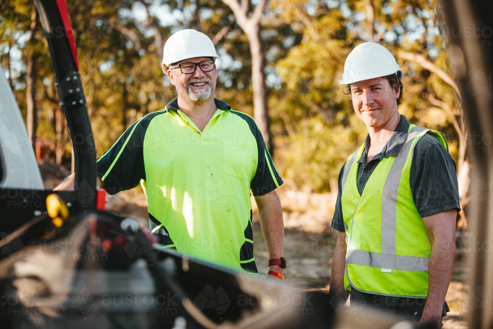 Image of Two builders standing next to a ute on worksite - Austockphoto