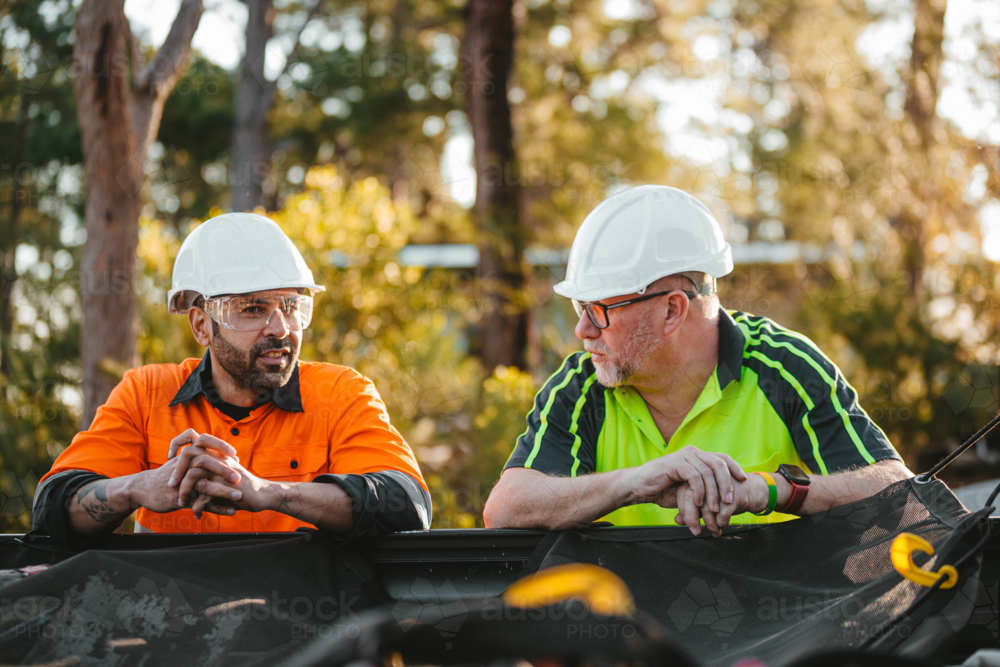 Image of Two builders standing next to the ute chatting - Austockphoto