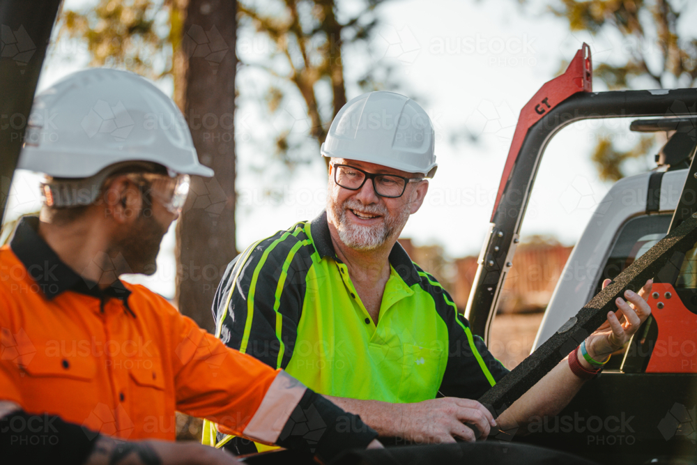 Image of Two builders standing next to the ute on worksite - Austockphoto