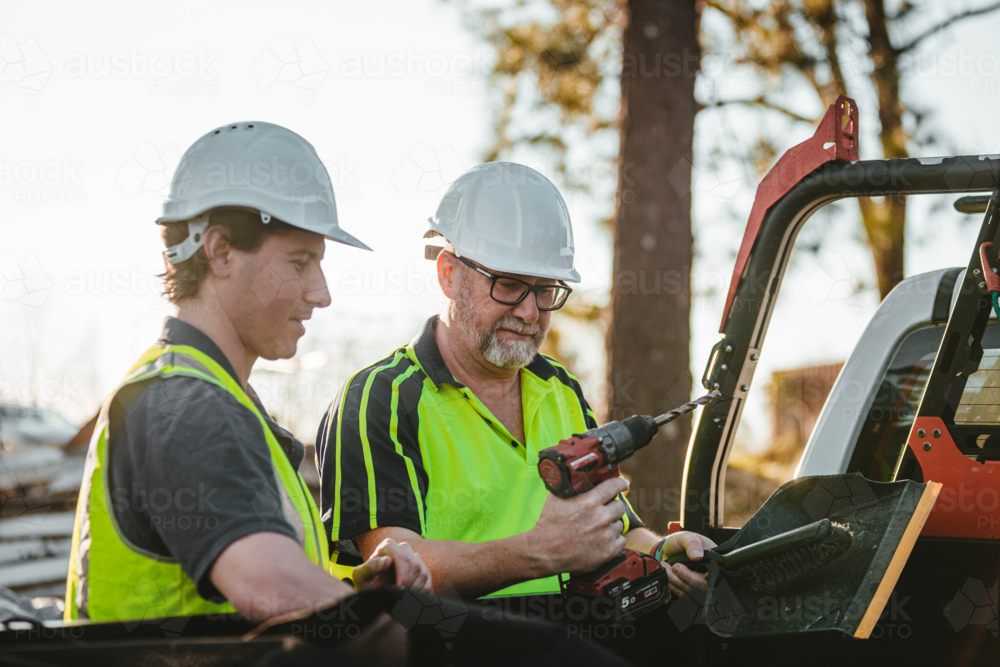 Image of Two builders standing next to ute on construction site one man ...