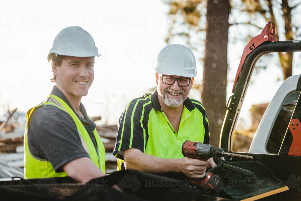 Image of Two builders standing next to ute on construction site one man ...