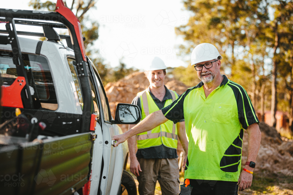 Image of Two builders standing next to ute on worksite - Austockphoto