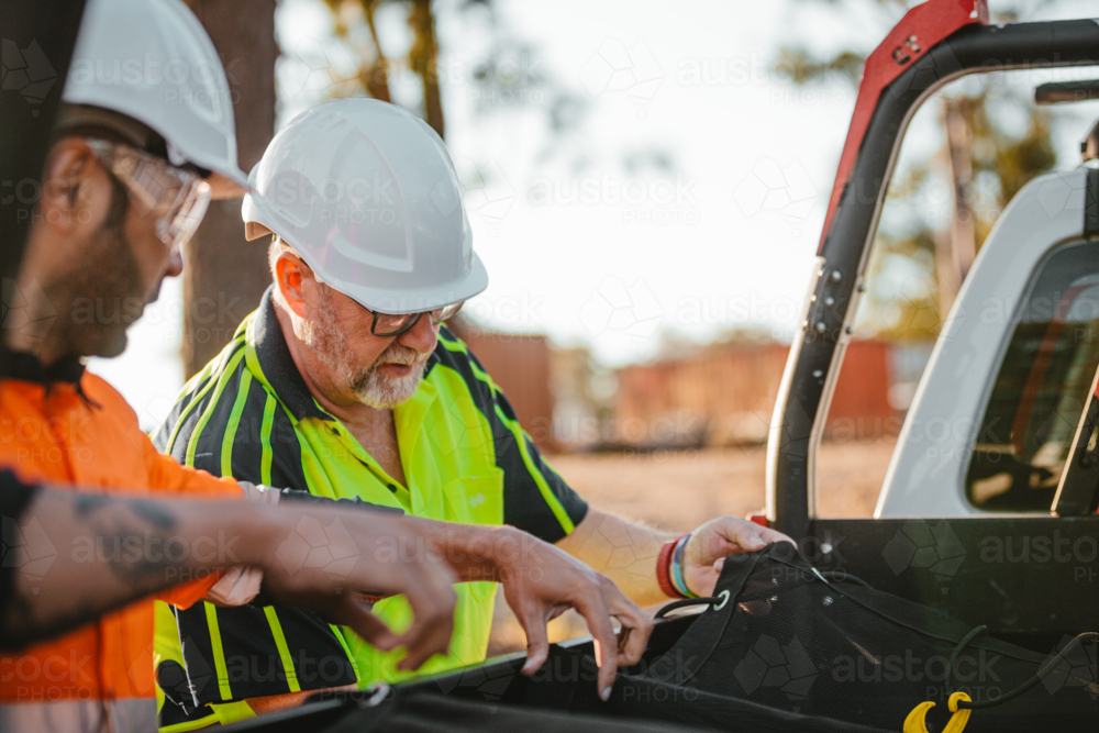 Image of Two builders standing next to ute on worksite - Austockphoto