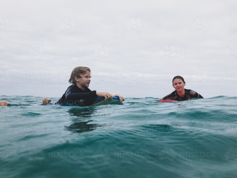 Image of Two children floating on boards in ocean on overcast day ...