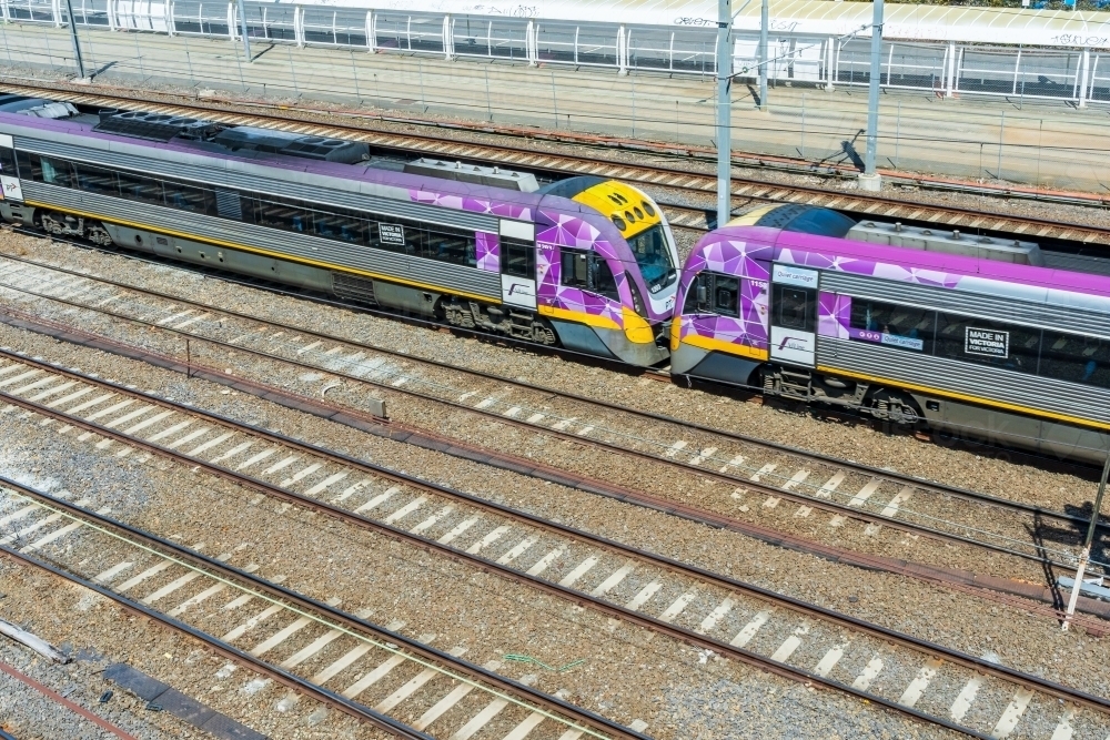 Image of Two commuter trains end to end speeding through a railway yard ...