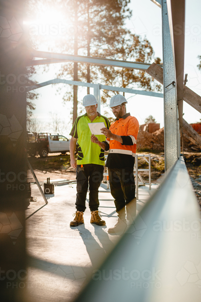 Image of Two construction site managers looking at digital blueprints ...