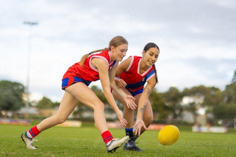 Image of two female football players bending and reaching for ball ...