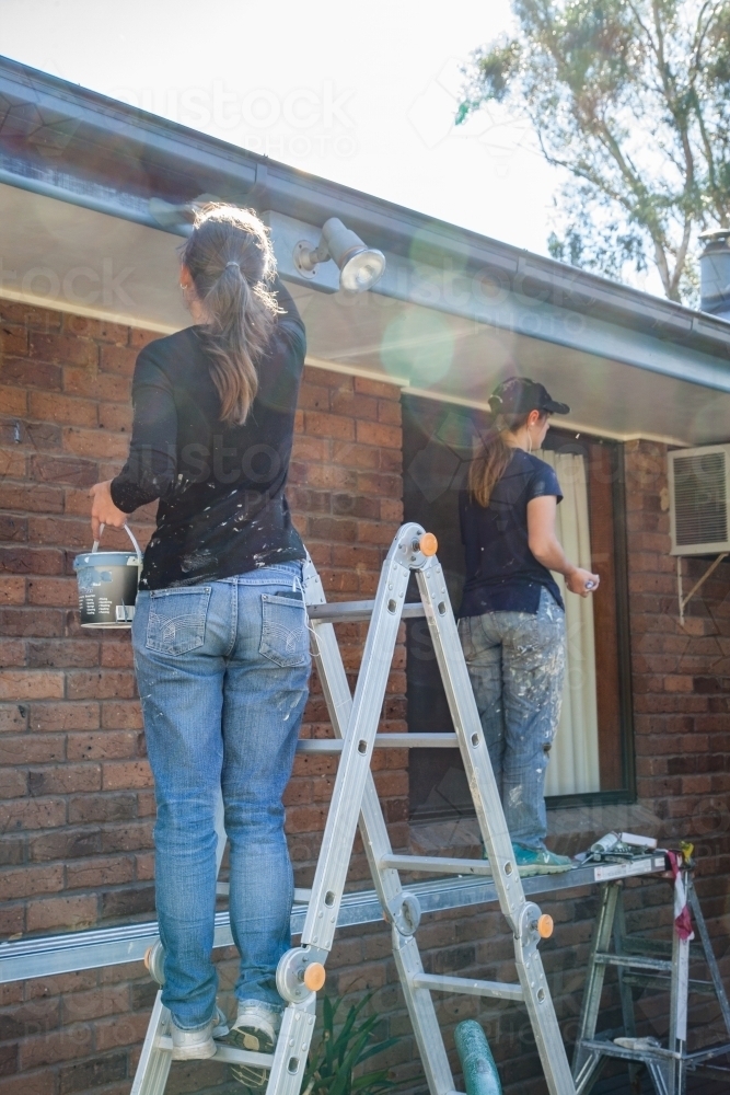 Image of Two female painters Painting home exterior - Austockphoto