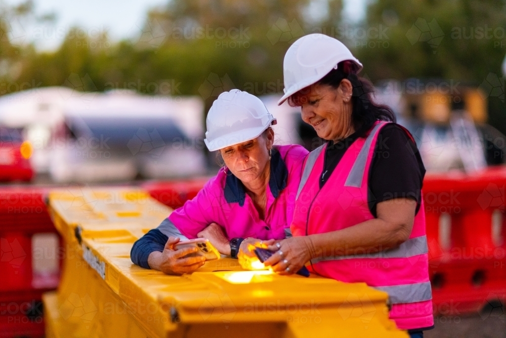Image of two female workers in hi vis and hard hats looking at their ...