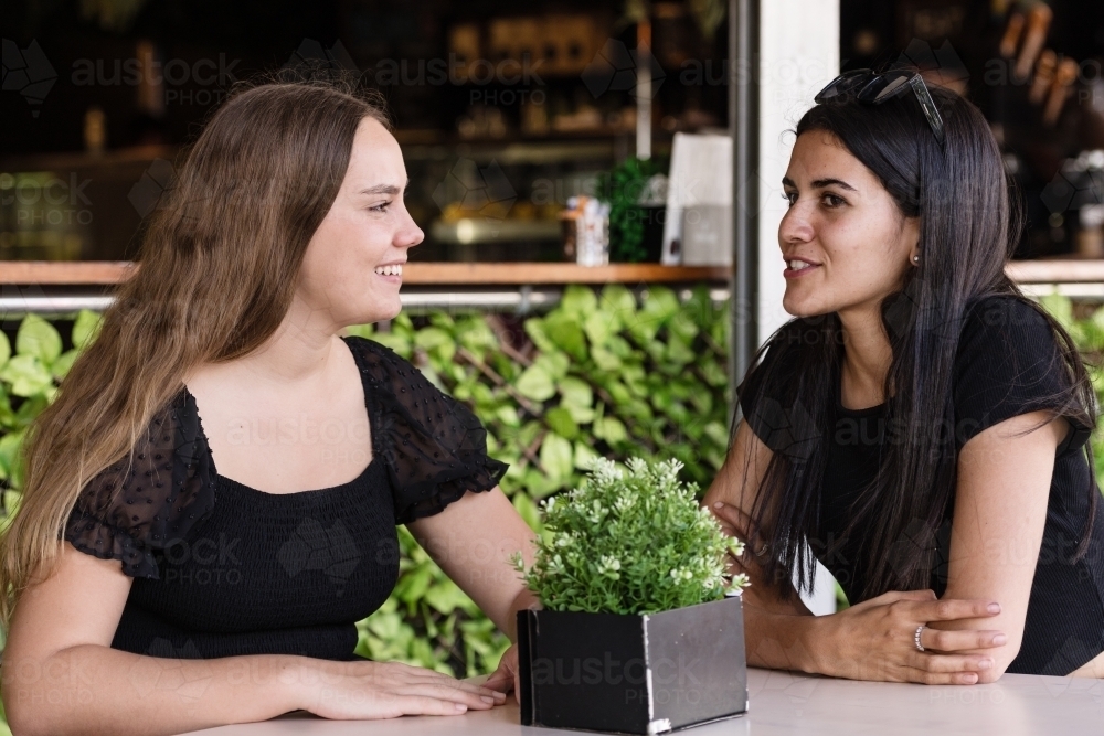 Image of two friends chatting in a cafe - Austockphoto