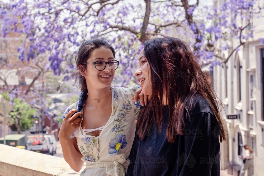 Image of two friends chatting under jacaranda trees - Austockphoto