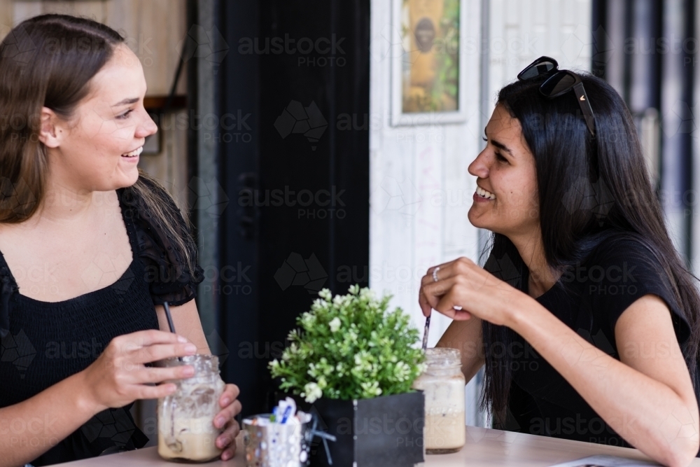 Image of two friends enjoying a coffee in a cafe - Austockphoto