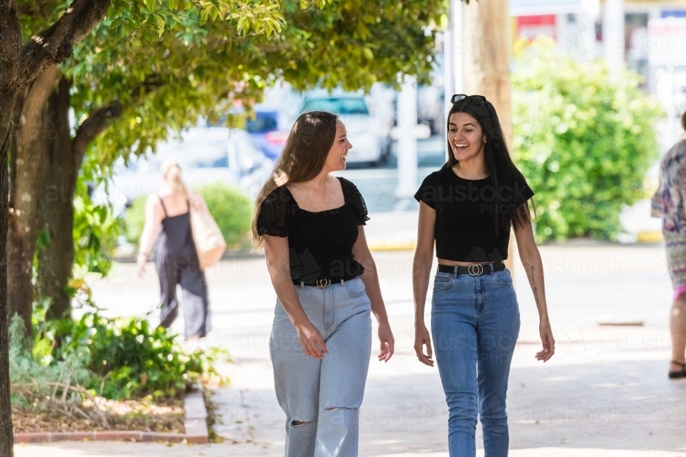 Image of two friends walking in the street - Austockphoto