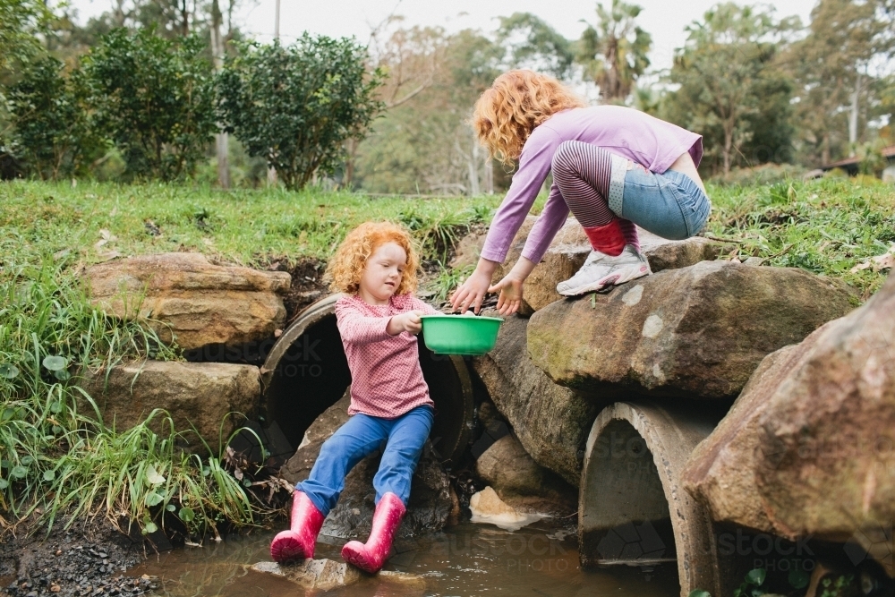 Image of Two girls playing near a stormwater drain - Austockphoto