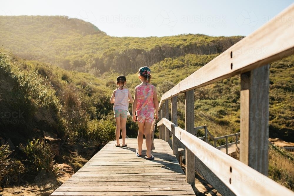 Image of Two girls walking along a boardwalk - Austockphoto