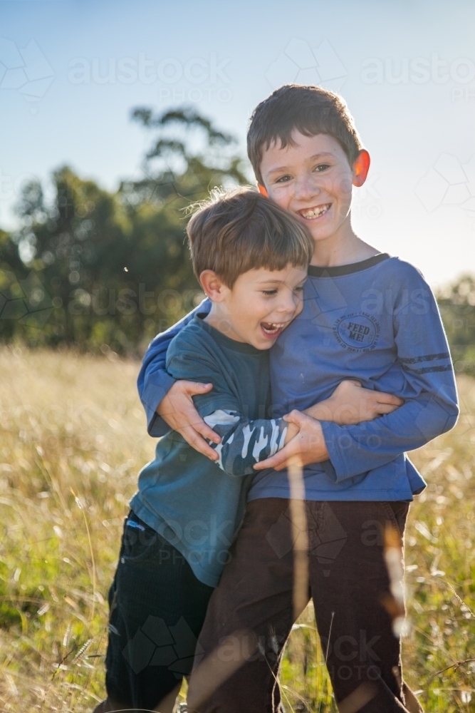 Image of Two happy boys being kids together outdoors - Austockphoto