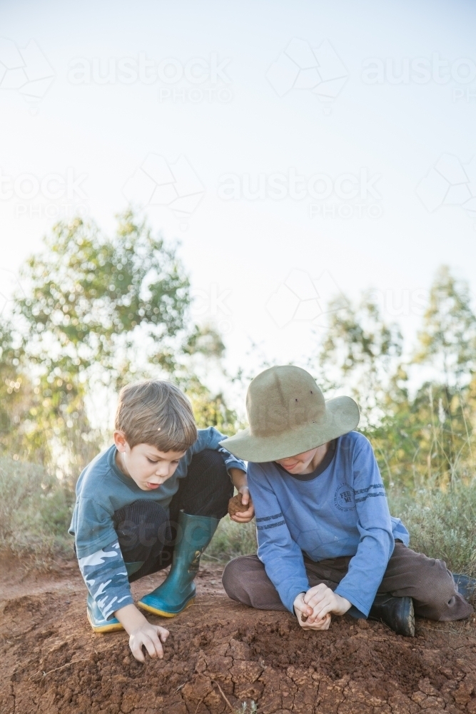 Image of Two happy boys playing in the dirt outside - Austockphoto