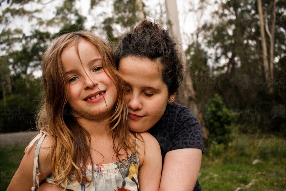 Image of Two happy girls smiling together hugging outside in bushland ...