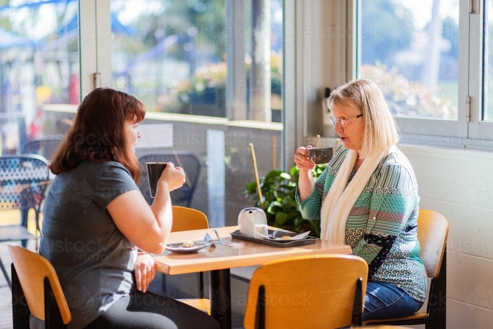 Image of Two happy ladies catching up over coffee at a local cafe ...