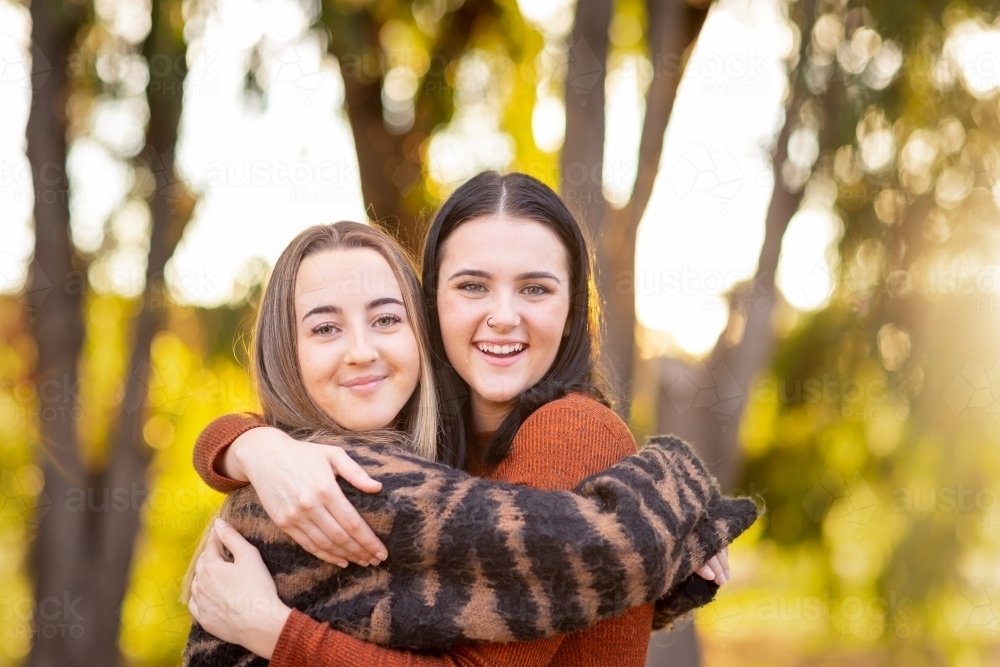Image of two happy teen girls looking at camera with arms around each ...