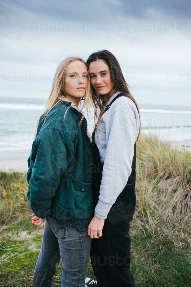 Image of Two hip young girls stand cheek to cheek by the sea - Austockphoto