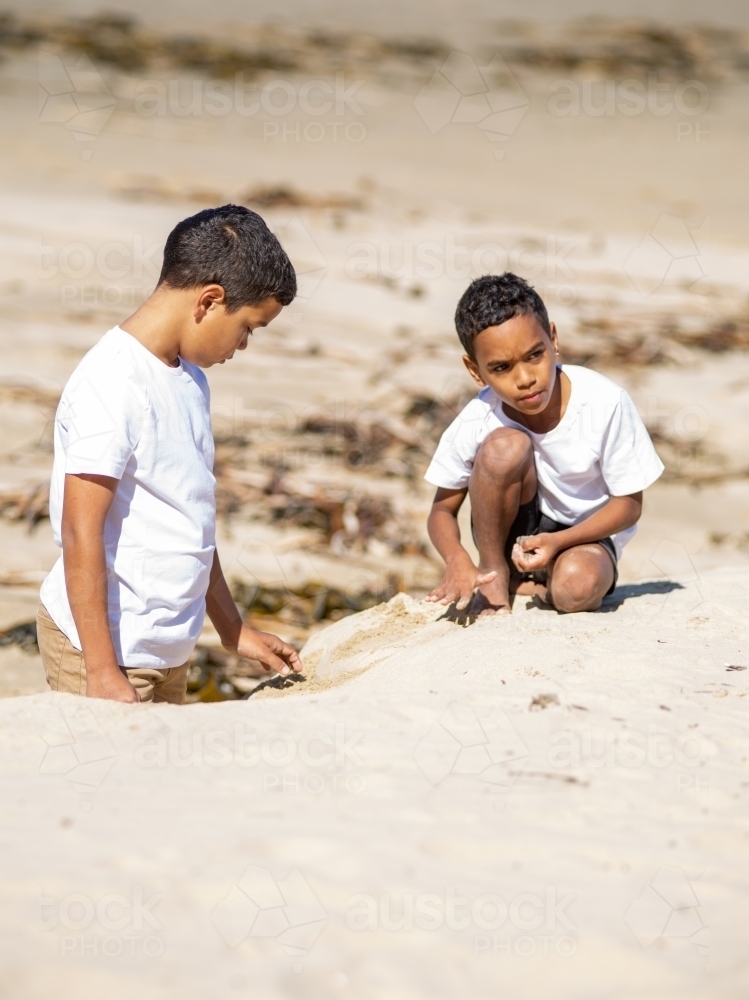 Image of Two indigenous boys playing in the sand - Austockphoto