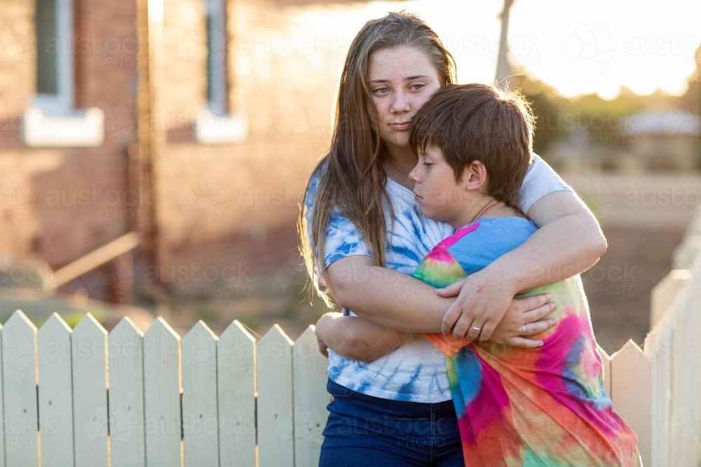 Image of Two kids embracing outside an old house - Austockphoto