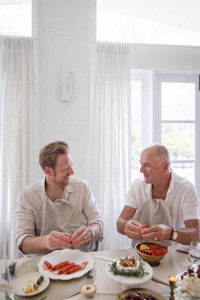 Image of Two men deveining prawns at dinner table - Austockphoto