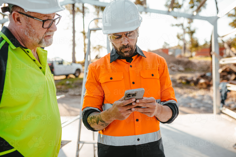 Image of Two men wearing safety gear on the construction site with one ...