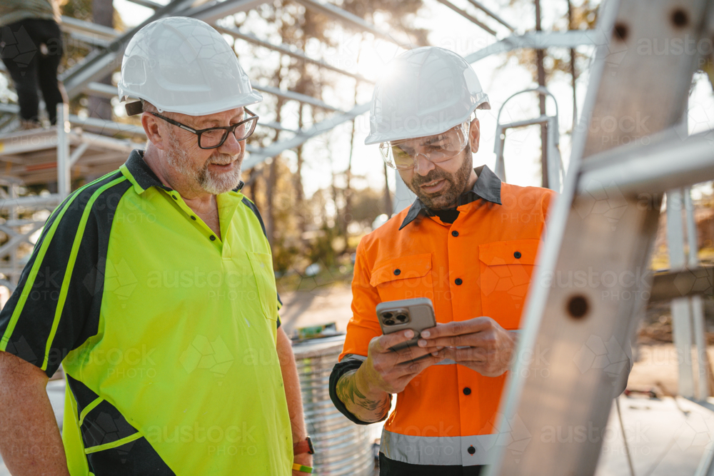 Image of Two men wearing safety gears on the site with one holding a ...