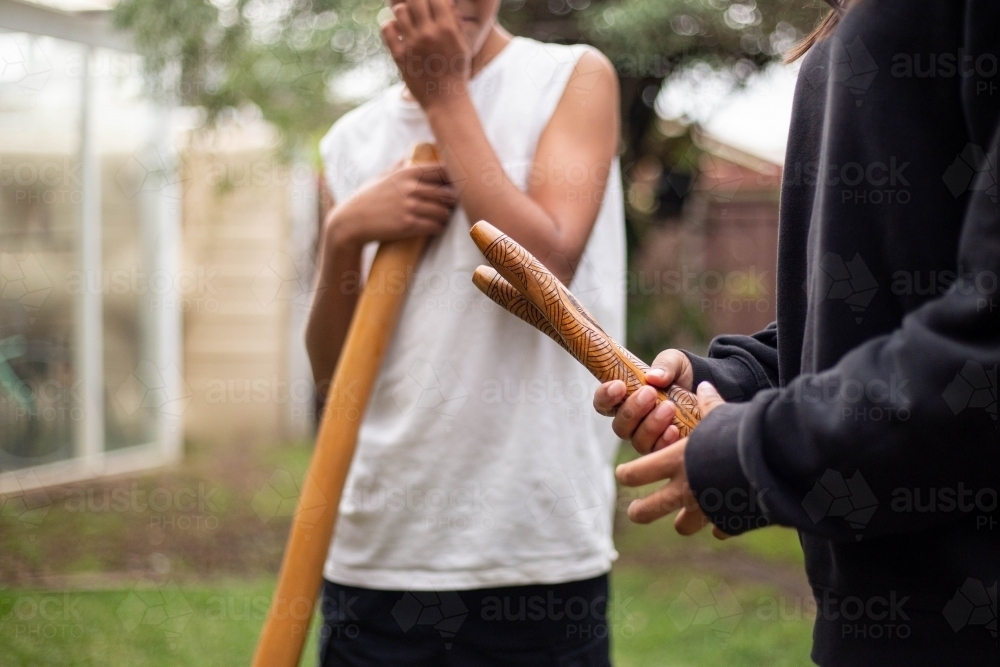 Image of Two people holding Aboriginal instruments in backyard ...