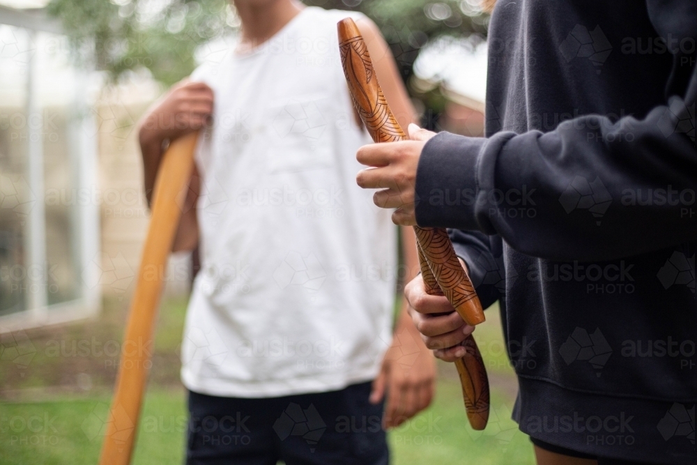 Image of Two people holding Aboriginal instruments in backyard ...