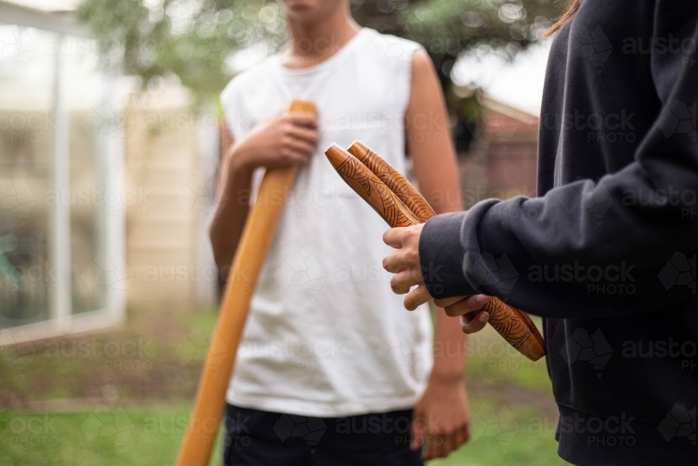 Image of Two people holding Aboriginal instruments in backyard ...