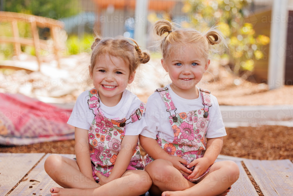 Image of Two preschool sisters in pink happily sitting together ...