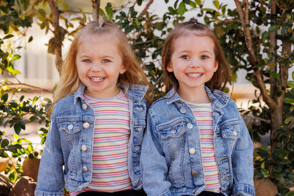 Image of Two preschooler sisters sitting together in kindergarten yard ...