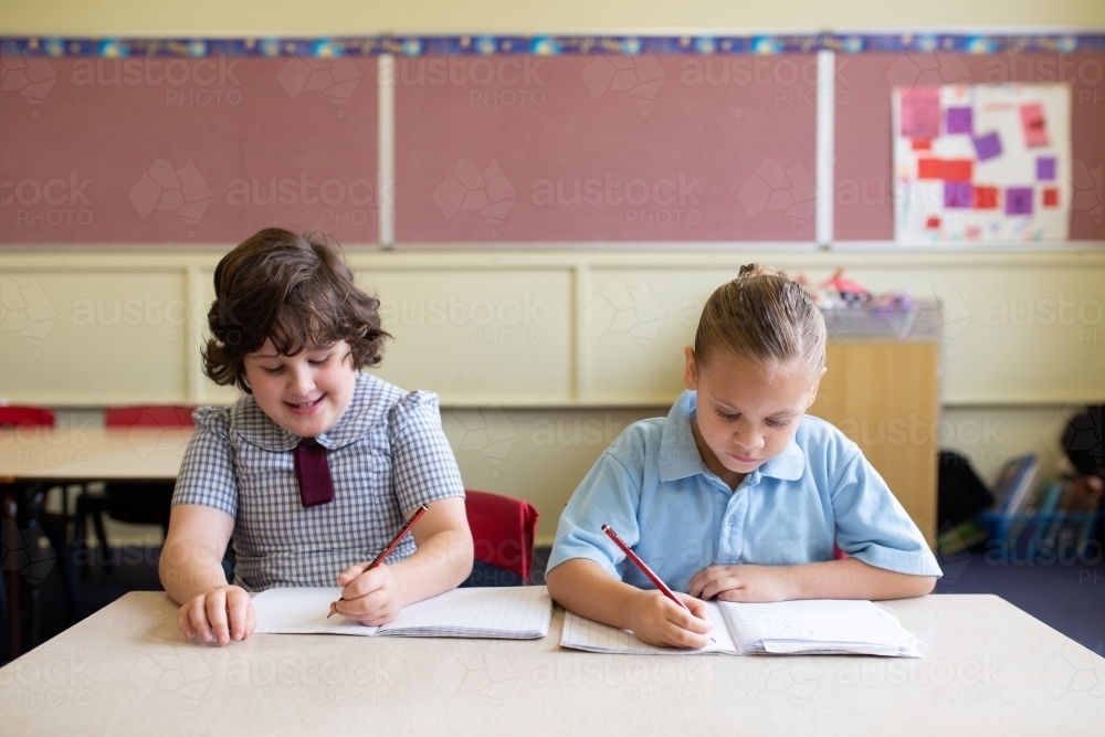 Image of Two primary school girls sitting working in a classroom ...