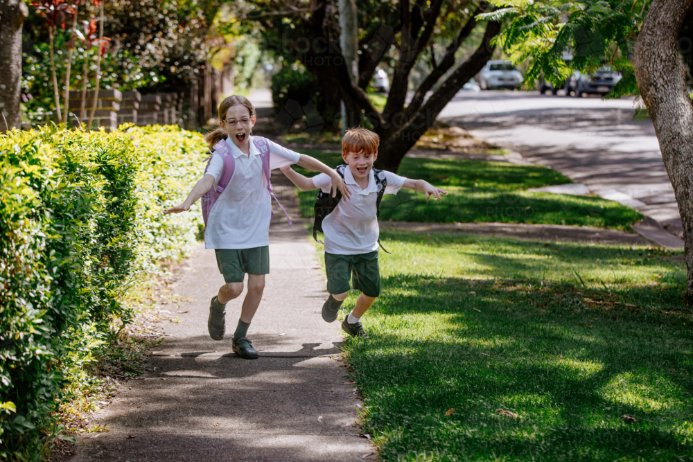 Image of Two school kids running on the pathway. - Austockphoto