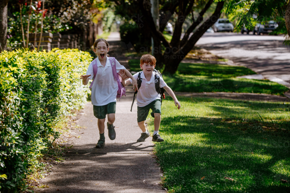 Image of Two school kids running on the pathway. - Austockphoto